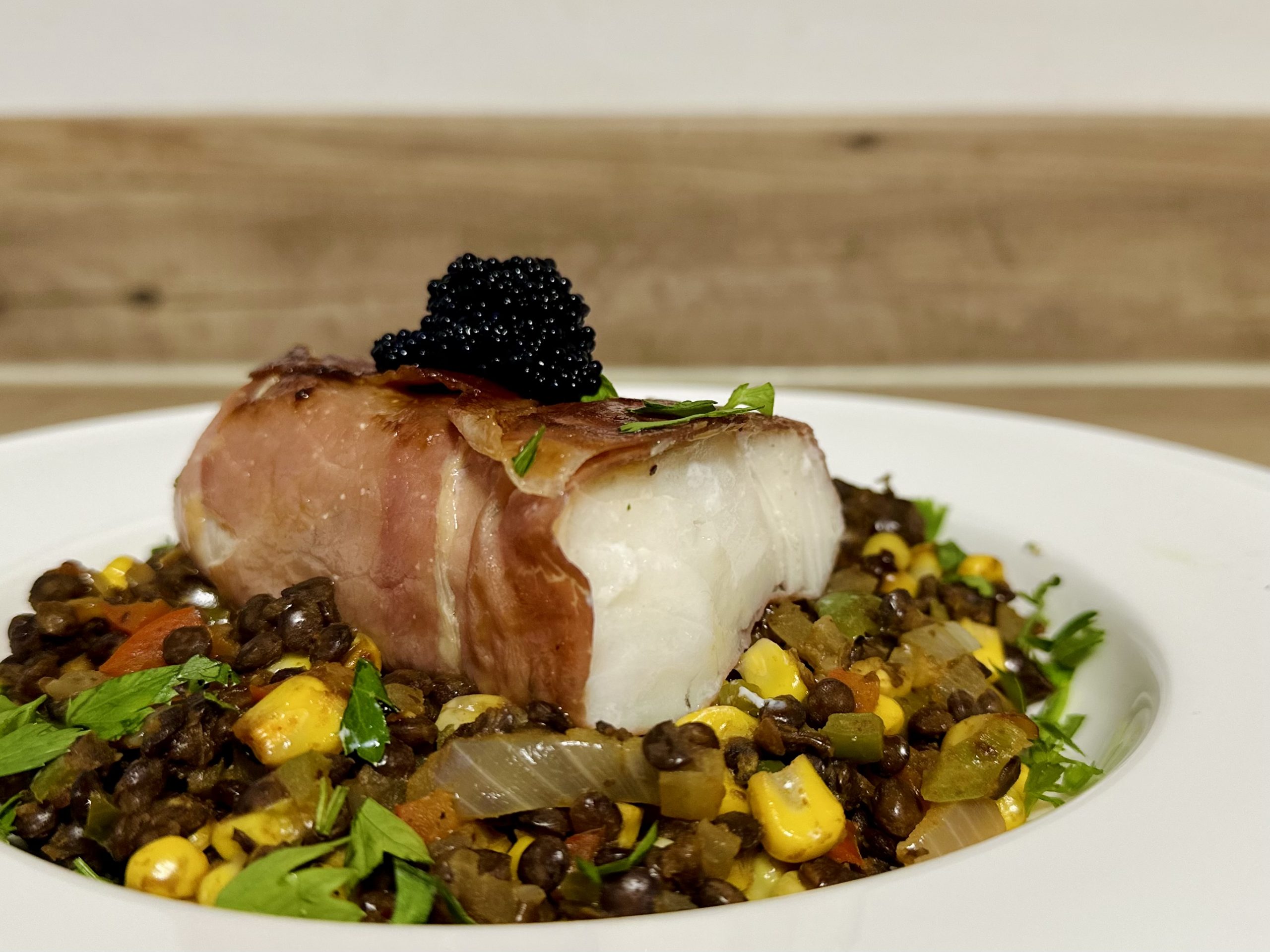 Prosciutto wrapped cod with puy lentil, sweetcorn and peppers